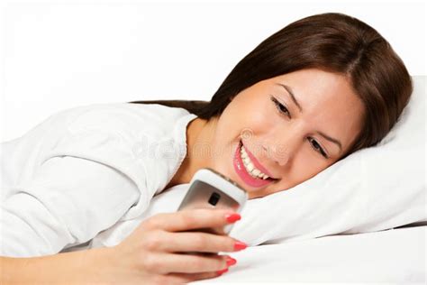 Happy Woman Lying On Bed Smiling Reading A Text Message Stock Photo