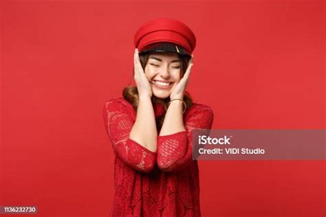 레이스 드레스와 모자를 유지 눈을 닫힌 웃는 젊은 여자의 초상화 밝은 빨간색 벽 배경에 고립 된 얼굴에 손을 넣어 사람들은