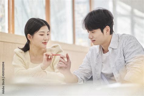 아시아 한국의 대학교 강의실 책상에 앉아서 마주보고 이야기하는 젊은 남녀 대학생 모델 Stock 사진 Adobe Stock