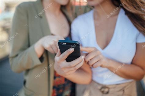 Two Young Girls Using Mobile Phone They Areon The Bridge Close Stock