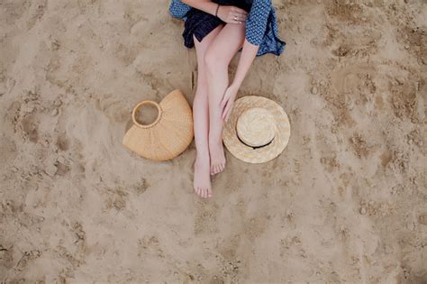 모래 해변에 여자 무두질 다리 밀짚 모자와 가방 여행 개념 모래 위에 발을 딛고 해변에서 휴식을 취하십시오 관광에 대한 스톡