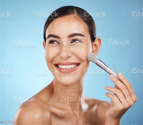 화장품 행복하고 스튜디오의 파란색 배경에 격리된 메이크업 브러시를 가진 여성 스킨케어 뷰티 모델 생각 미용 파운데이션 몸 건강을