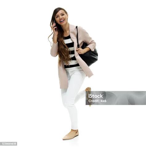 흰색 배경 앞에서 걷는 백인 여성은 블레이저를 입고 지갑을 들고 휴대 전화를 사용합니다 30 34세에 대한 스톡 사진 및 기타 이미지 30 34세 30 39세 갈색