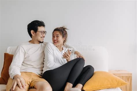 Happy Lovely Asian Couple Sharing Smartphone To Watch Together In