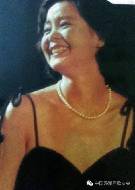 A Woman In A Black Dress Smiling And Wearing A Pearl Necklace With Her