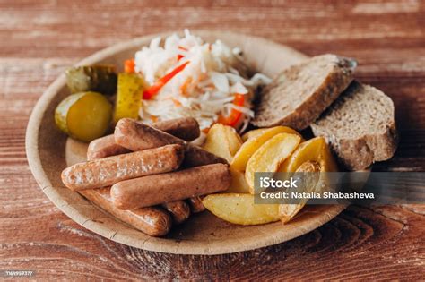 Ntasty 소시지 튀김 감자 오이 양배추와 클로브 나무 테이블에 종이 접시에 테이크아웃 길거리 음식 갈색에 대한 스톡 사진 및 기타 이미지 Istock