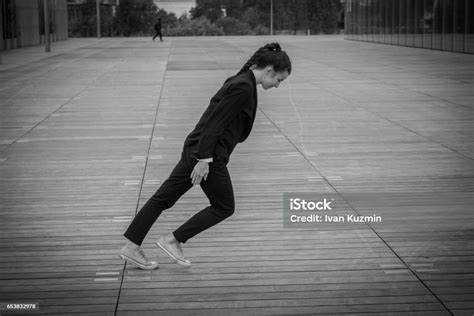 엄격한 흑백 재킷을 입은 아름다운 젊은 여성이 현대적인 비즈니스 지구의 목조 에스플러네이드에서 현대 무용을 움직입니다 공연에