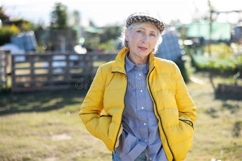 Anciana Seria Con Chaqueta Amarilla Mirando La Cámara Mientras Se Queda