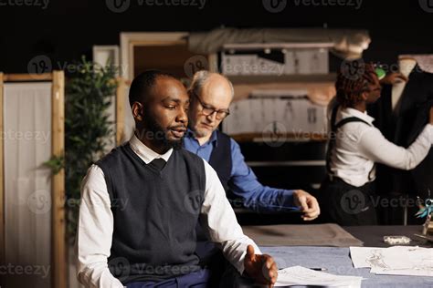 Master Tailor Taking Client Measurements While Meticulous Seamstress