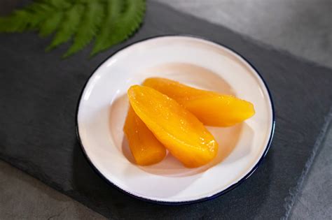시럽에 고구마 또는 얌은 일반적으로 검은 돌 배경에 빈티지 아연 코팅 접시에 코코넛 밀크를 제공 태국의 전통 디저트 갈색에 대한