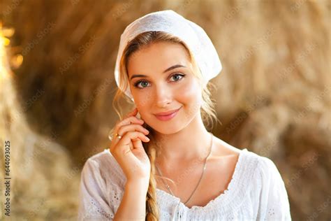 Beautiful Blonde Girl With Braided Hair In White Rural Clothes Sitting