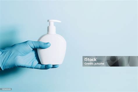 파란색 배경에 비누 병과 의료 용 얼굴 마스크를 들고 장갑에 손 공간을 복사합니다 코로나바이러스로부터 보호하기 위한 예방 조치