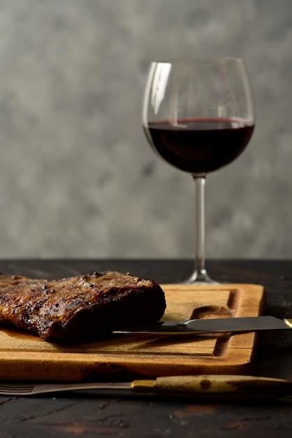 Premium Photo Roasted Beef Ribs With A Glass Of Red Wine Presented On