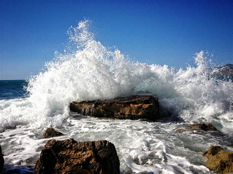 青い空の下で海の波と岩の多い海岸：無料の写真素材