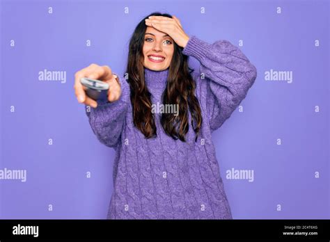 Young Beautiful Woman Using Television Remote Control Over Isolated