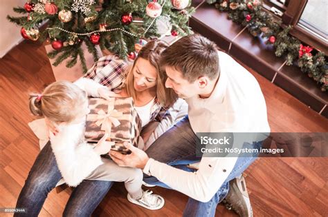 금발의 어머니 아버지와 선물을 열어 재미 그들의 가정에 있는 크리스마스 트리 옆에 앉아 귀여운 소녀 위에서 볼 수 있습니다 베오그라드 세르비아 유럽 12월 31일에 대한