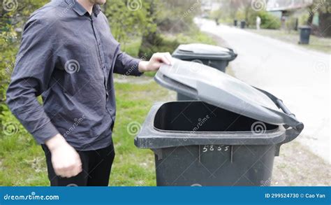 Man Throwing Out Black Eco Friendly Recyclable Trash Bag In To Big