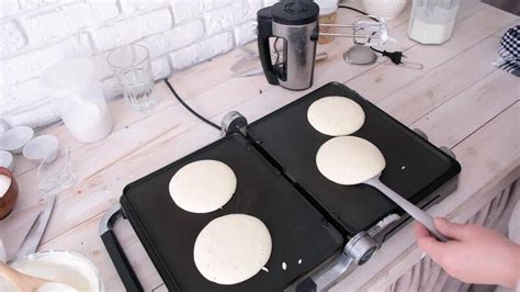 Middle Aged Woman Cooking Pancakes On Grill Panels In The Kitchen