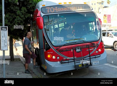 Man Waiting At Bus Stop Getting On 704 Metro Rapid Bus To Go Downtown