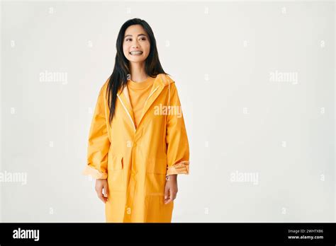 Young Smiling Asian Woman With Braces Wearing Bright Yellow Raincoat