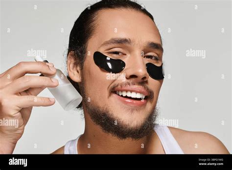 A Young Bearded Man Smiles While Applying Facial Patches Embracing