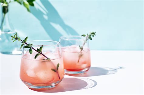 여름 자몽 칵테일 하드 섀도우가 있는 햇빛에 허브가 있는 신선한 건강한 자몽 음료 파란색 파스텔 배경에 야자수 잎이있는 창조적 인 음료 목테일에 대한 스톡 사진 및 기타