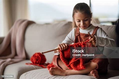 소파에 앉아 집에서 실내에서 뜨개질을 배우는 어린 소녀 뜨개질하기에 대한 스톡 사진 및 기타 이미지 뜨개질하기 아이 가정 생활 Istock