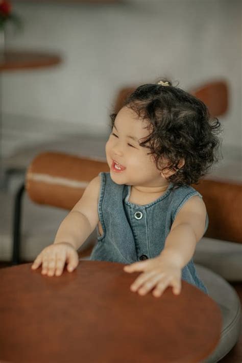 갈색 머리 곱슬머리 귀여운 미소 짓는 셀렉티브 포커스 소녀 수직 쐈어 아기 앉아 있는 어린 시절 청바지 드레스