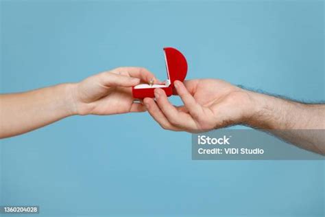 스튜디오에서 파스텔 블루 컬러 배경에 고립 된 결혼을 제안 결혼 반지와 손 빨간 상자에 여성 남성의 자른 사진을 닫습니다 발렌타인 데이 휴일 개념 약혼식에 대한 스톡 사진