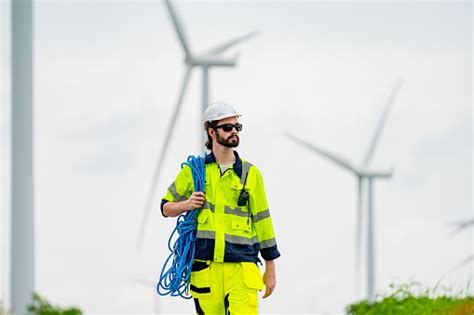 구름이 낀 날 밝은 안전 장비를 착용하고 풍력 발전 단지 현장에서 도구와 장비를 가지고 걷고 있는 엔지니어 건설 산업에 대한 스톡 사진 및 기타 이미지 Istock