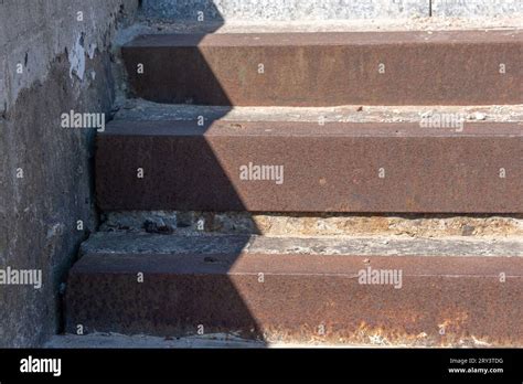 Metal And Concrete Old Rusty Steps With Shadow Next To Concrete Wall