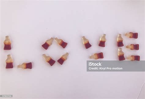 사랑이라는 단어는 분홍색 매트 마멀레이드 배경에 배치되어 있습니다 레모네이드병 형태의 젤라틴 사탕 발렌타인 데이 사랑과 평화