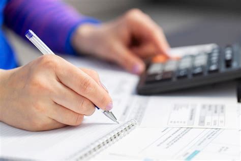 Mujer usando calculadora para calcular facturas domésticas en casa haciendo papeleo Foto Premium