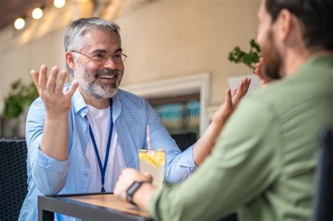 Two Men Sitting In The Cafe And Having An Interesting Conversation