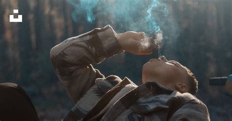 A Man Sitting In A Chair With A Cigarette In His Mouth Photo Free Man
