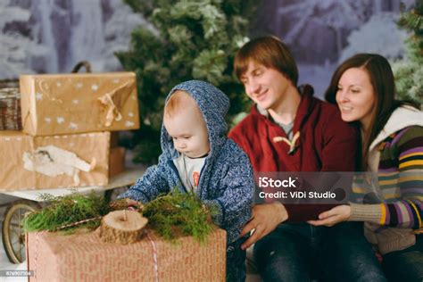 전나무 나무 썰매와 선물 상자 장식된 숲에서 귀여운 작은 아기와 젊은 장난 행복 한 부모 크리스마스 좋은 분위기 새 해입니다 라이프 스타일 가족 및 관계 개념입니다 2018