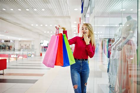 빨간 블라우스에 아름 다운 젊은 여자의 초상화는 캐주얼 청바지와 하이 힐 쇼핑몰에서 쇼핑백과 함께 포즈를 찢 어 가방에 대한 스톡 사진 및 기타 이미지 Istock