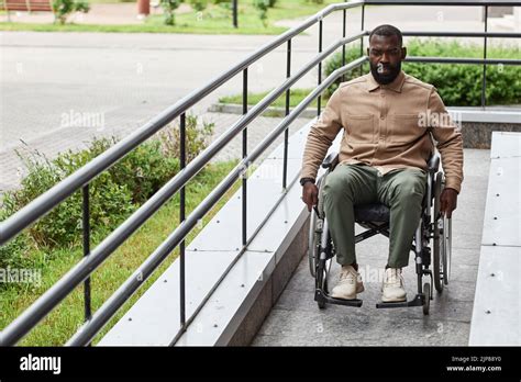 Full Length Portrait Of Adult Black Man With Disability Going Down Ramp In City Urban