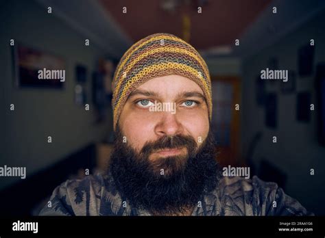 A Man With A Beard Wearing A Striped Hat And Shirt Looking Up Into The