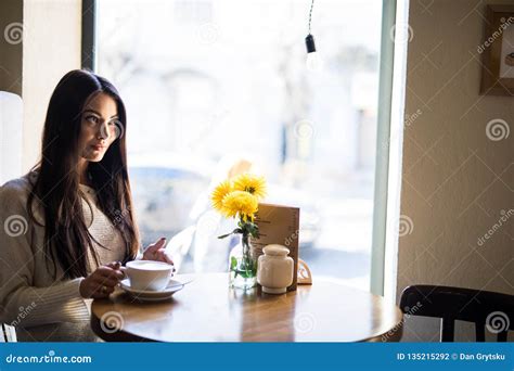 Beautiful Cute Girl In The Cafe Near The Window With Coffee Smiling And