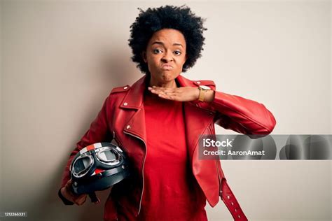 칼로 손으로 목을 절단 오토바이 헬멧을 들고 곱슬 머리를 가진 젊은 아프리카 계 미국인 Afro 오토바이 여자 분노 폭력으로