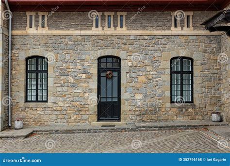 Stone Building Facade With Three Arched Windows And Wreath Adorned Door