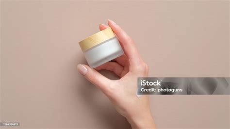 파스텔 베이지 색 배경에 화장품 크림 항아리를 들고 있는 여성 손 모이스처라이저 크림을 바르는 여성 쥠에 대한 스톡 사진 및 기타 이미지 Istock