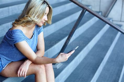 Girl Typing Message On Mobile Phone And Sitting On Stairs Stock Image