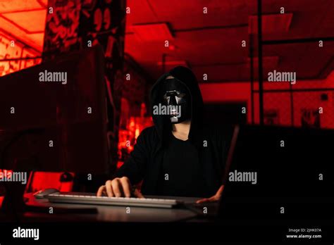 Dangerous Unrecognizable Hacker Man Wearing In Black Mask And Sweatshirt Hacking Online Web Site