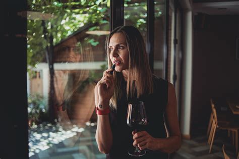 아름다운 여성이 와인 한 잔과 전자 담배를 들고 창문 옆에 서 있습니다 전자담배에 대한 스톡 사진 및 기타 이미지 전자담배 사람들 여자 Istock
