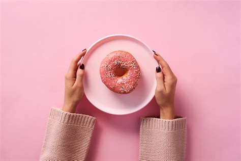 여성 손 핑크 배경 위에 접시에 도넛을 들고 평면도 평 신도 달콤한 디저트 다이어트 개념입니다 복사 공간이 있는 배너입니다 휴일