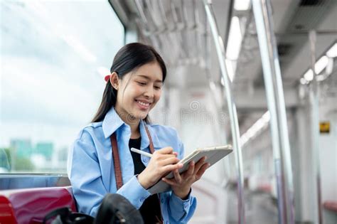 A Happy Beautiful Young Asian Female Passenger Using Her Digital