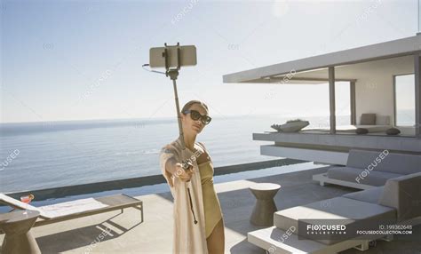 Woman In Bathing Suit Taking Selfie With Selfie Stick On Modern Luxury