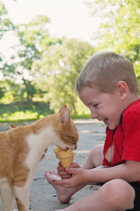 Muchacho De Risa Cosquilleado Por El Gato Que Come Su Helado Imagen De